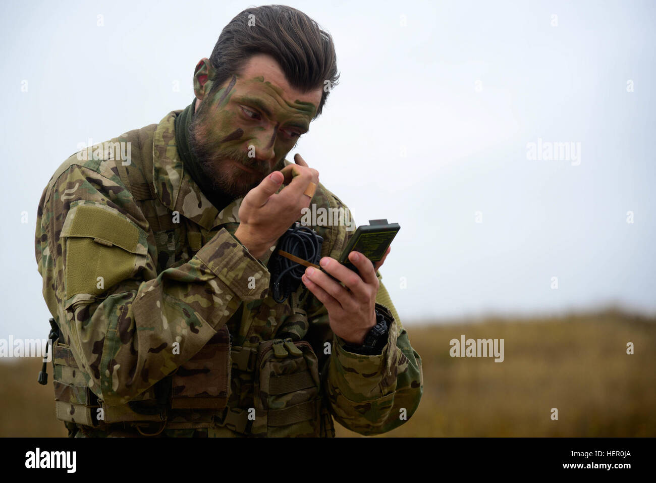 A Danish soldier applies face paint before taking part in the stalking ...