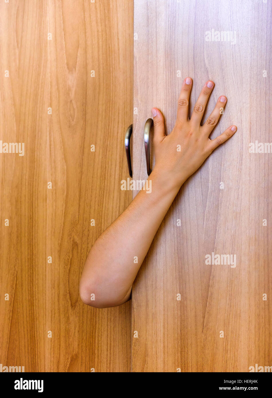 Person hand protruding from wardrobe door. Person inside of wardrobe ...