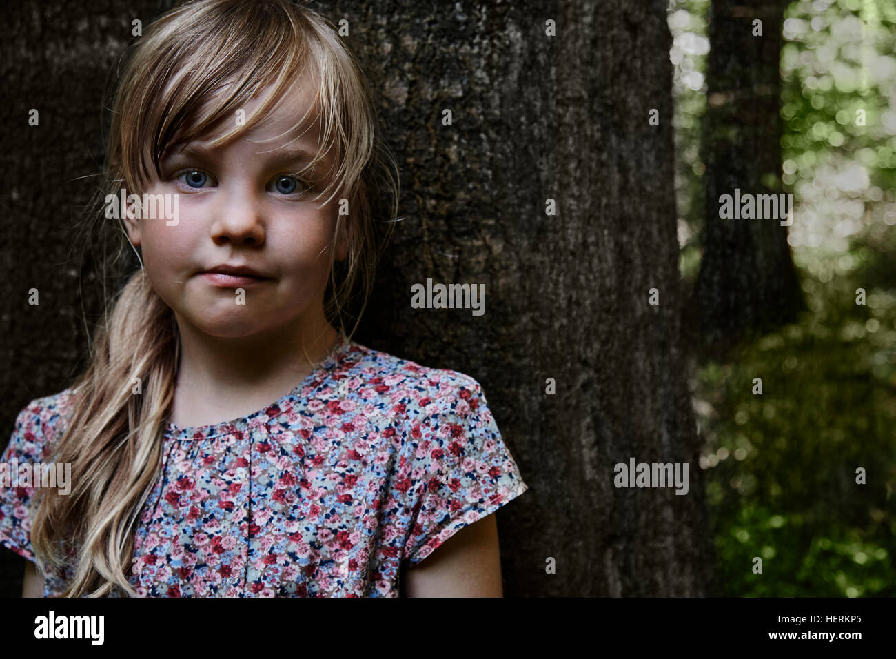 Portrait of a girl standing by a tree Stock Photo - Alamy