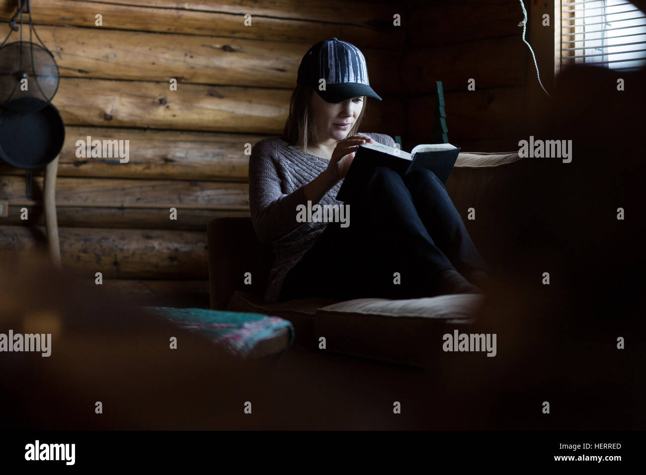 Woman sitting reading book in log cabin Stock Photo - Alamy