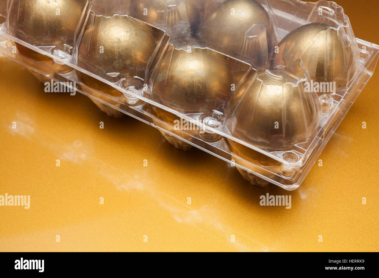 Golden eggs in a plastic box on golden background Stock Photo - Alamy
