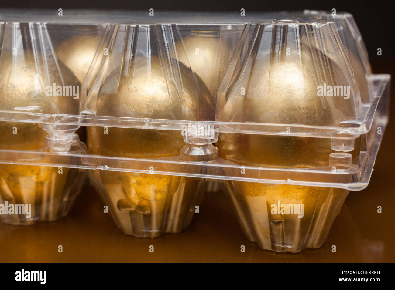 Golden eggs in a plastic box on golden background Stock Photo - Alamy