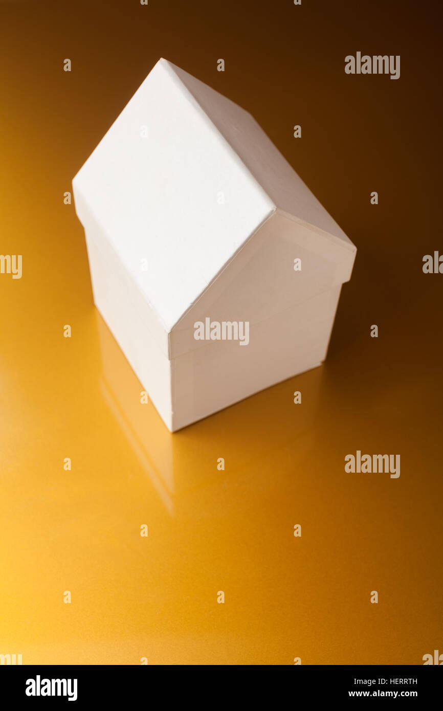 Cute white house, shaped box on golden background Stock Photo - Alamy
