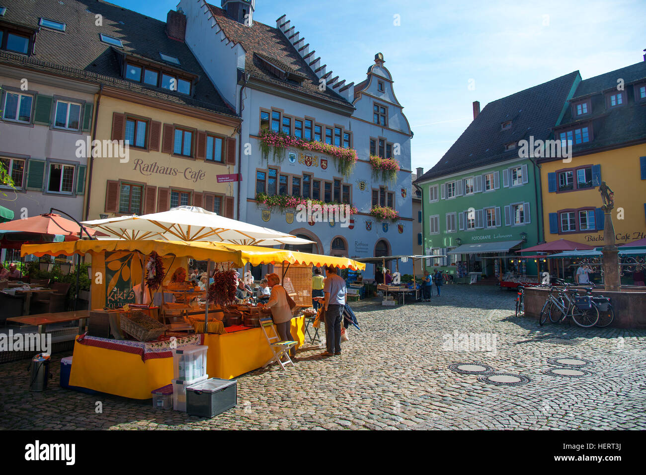 Market stalls in central cobbled square surrounded by buildings in ...