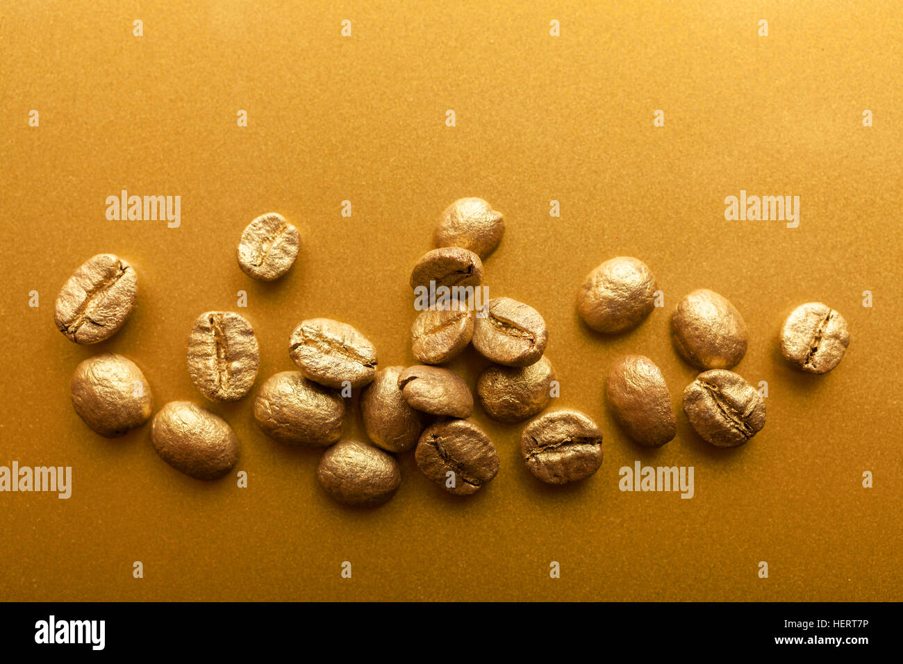 Golden beans of coffee on golden surface Stock Photo - Alamy