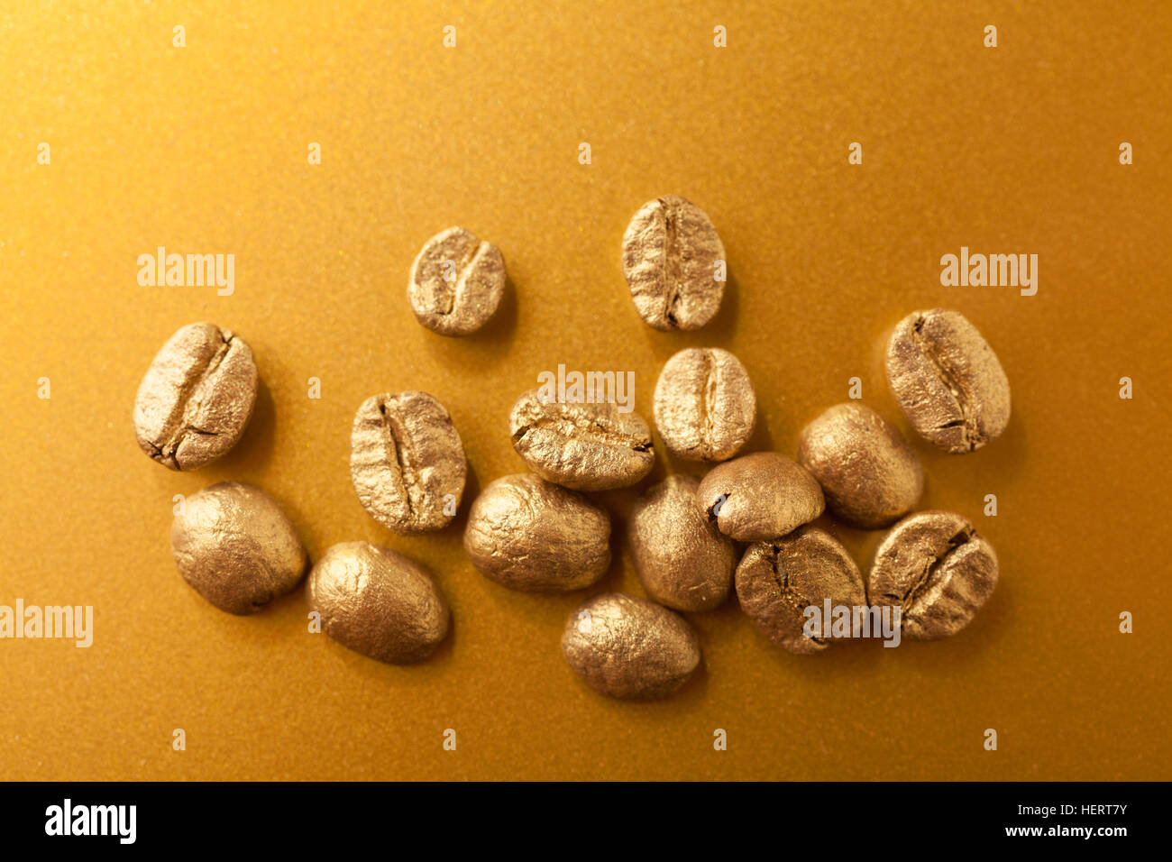 Golden beans of coffee on golden surface Stock Photo - Alamy