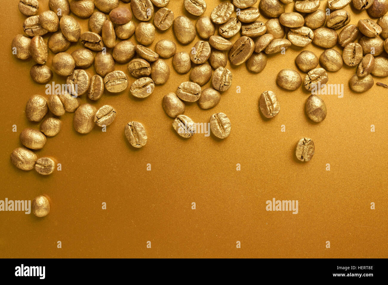 Golden beans of coffee on golden surface Stock Photo - Alamy