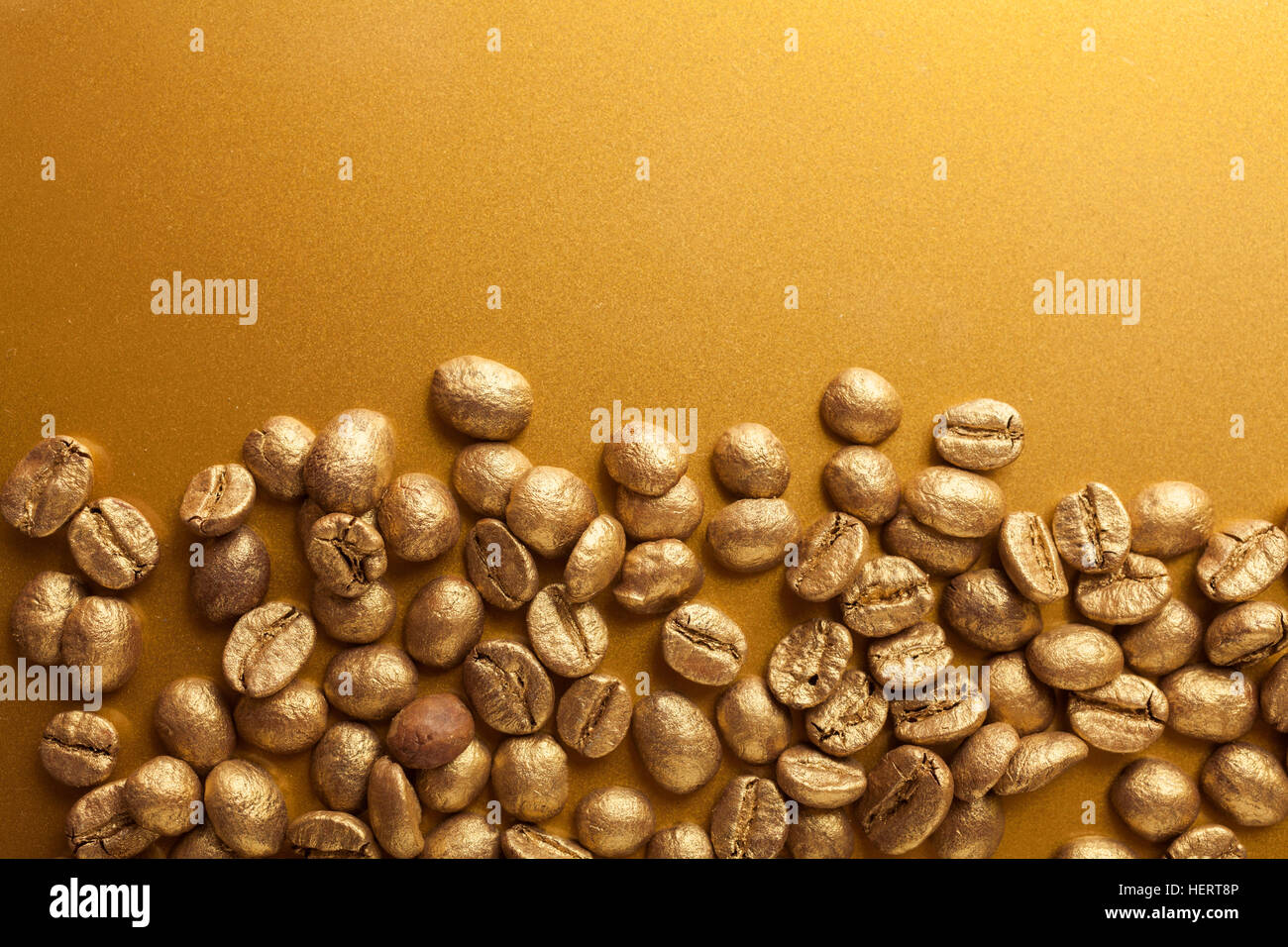Golden beans of coffee on golden surface Stock Photo - Alamy