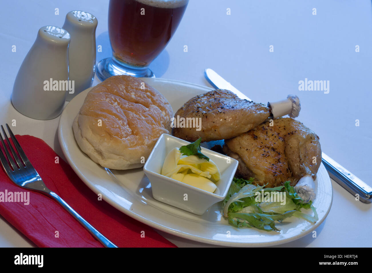 Oven roasted Chicken Legs served with salad and a fresh bread bun Stock ...