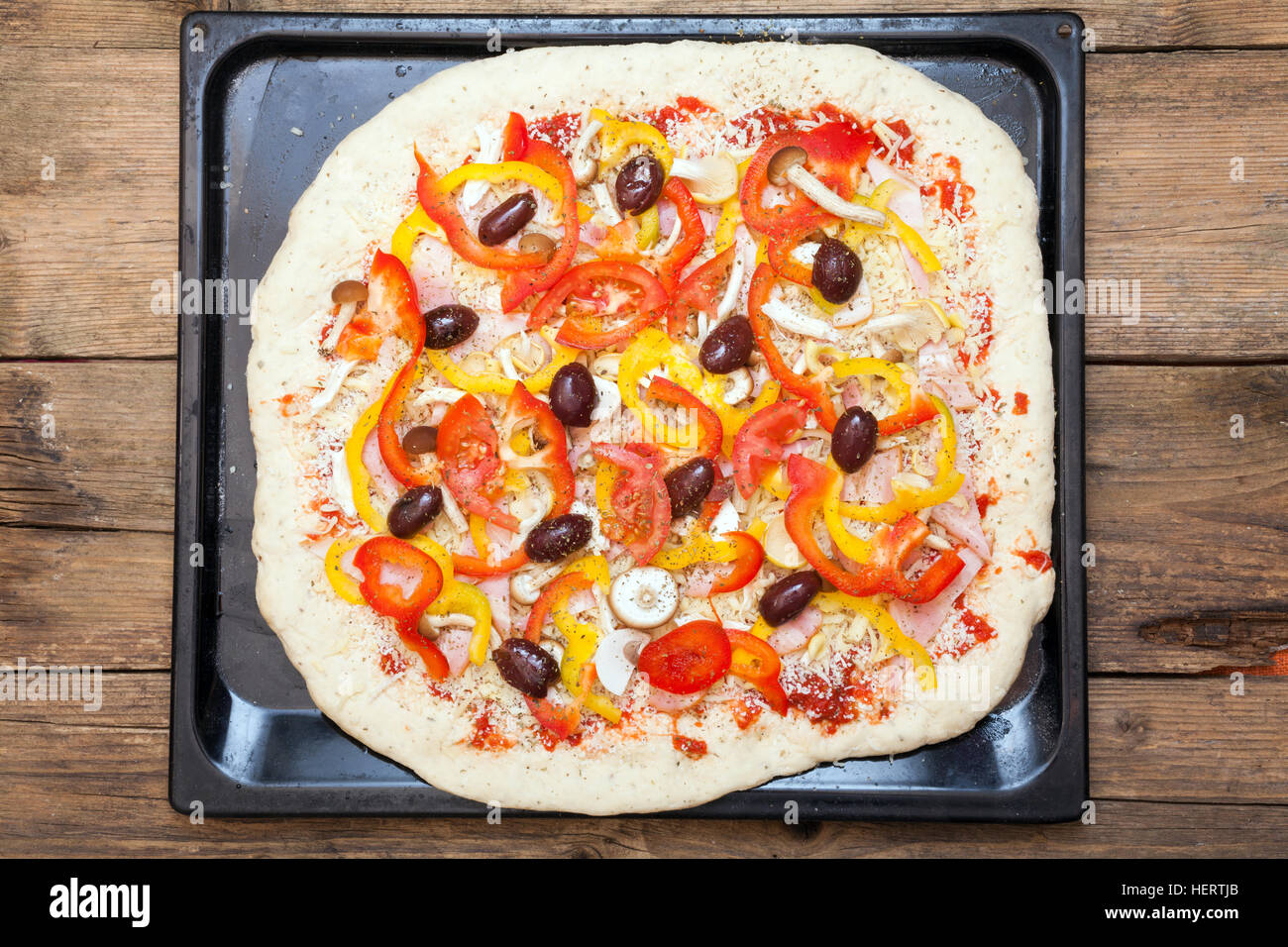 Preparing a pizza putting various ingredients over the dough before ...