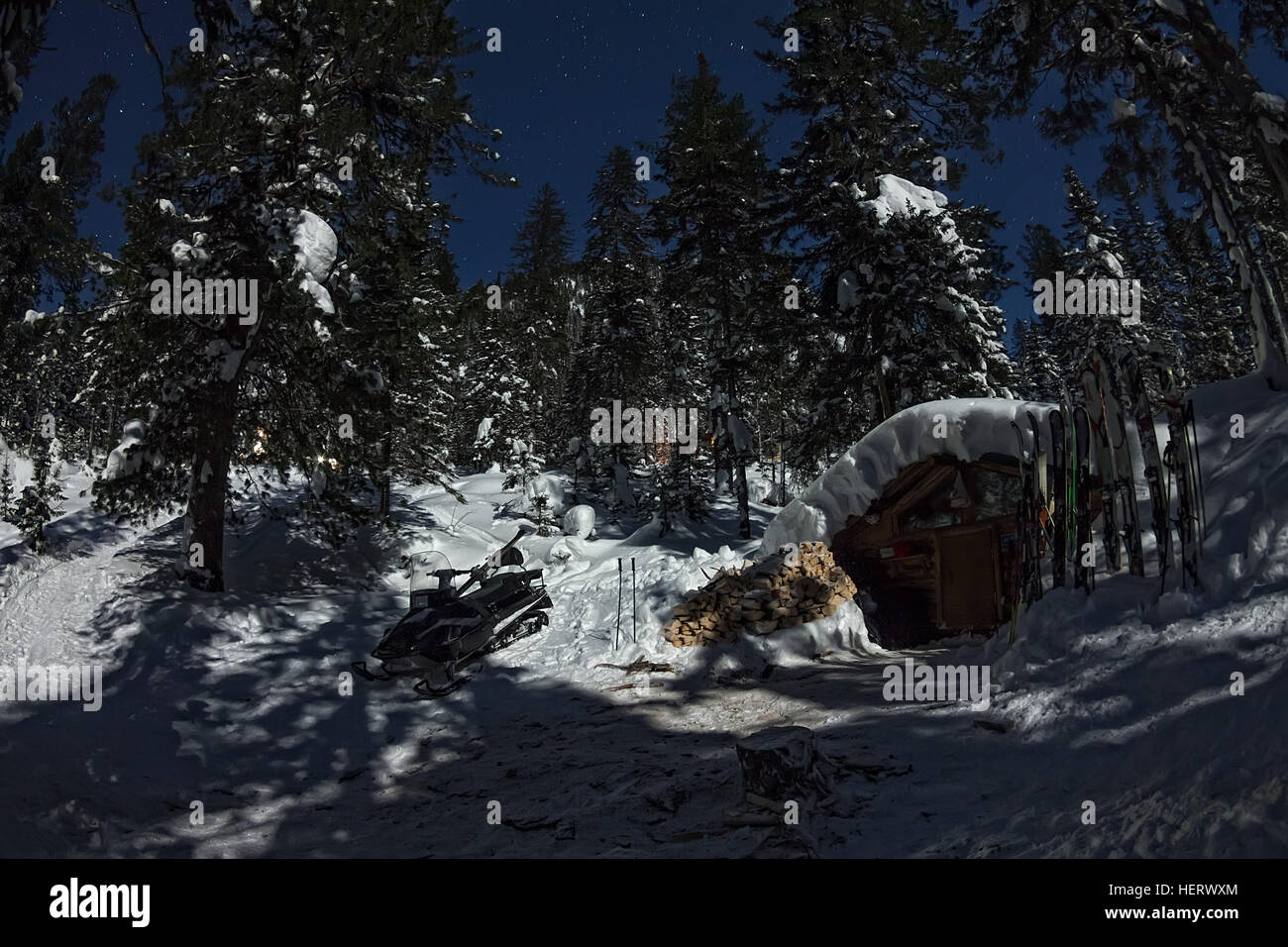 Snowmobile from house chalets in winter forest with snow in light moon ...