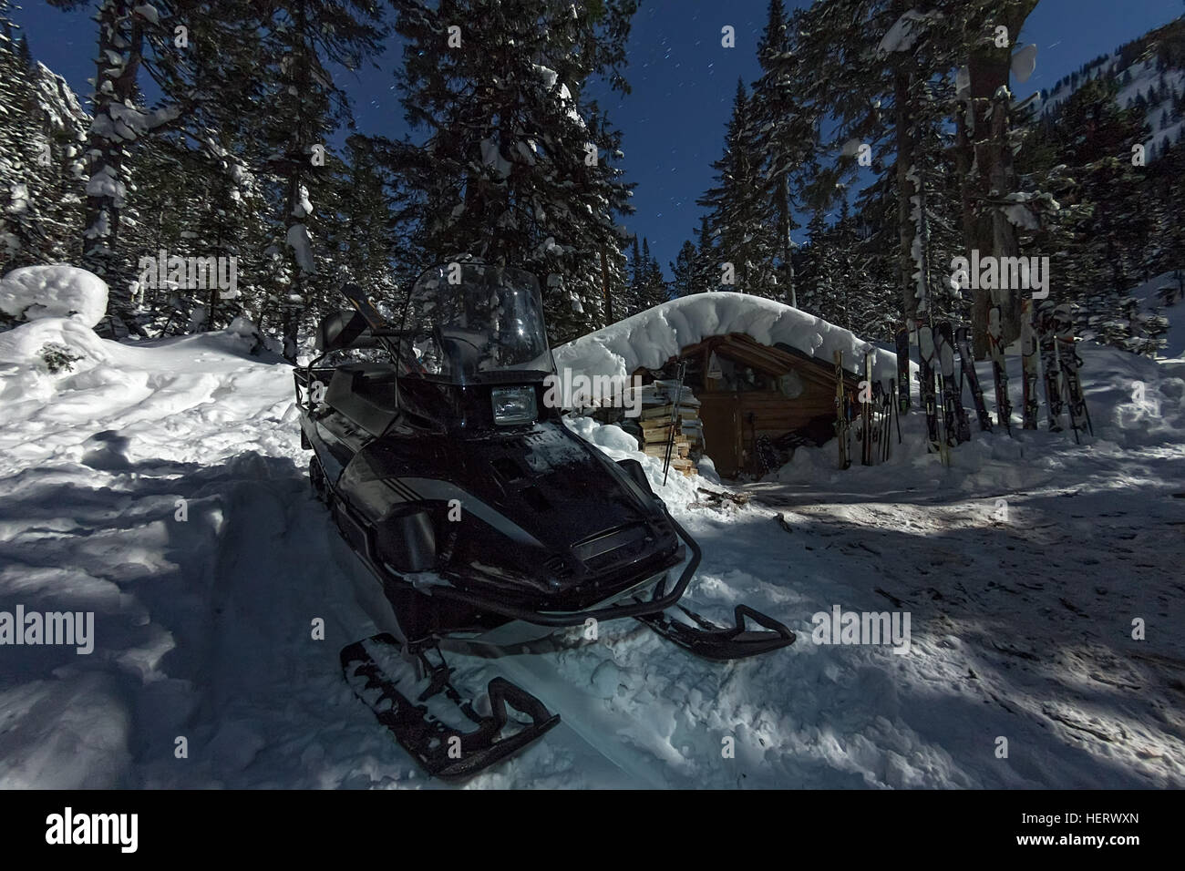 Snowmobile from house chalets in winter forest with snow in light moon ...