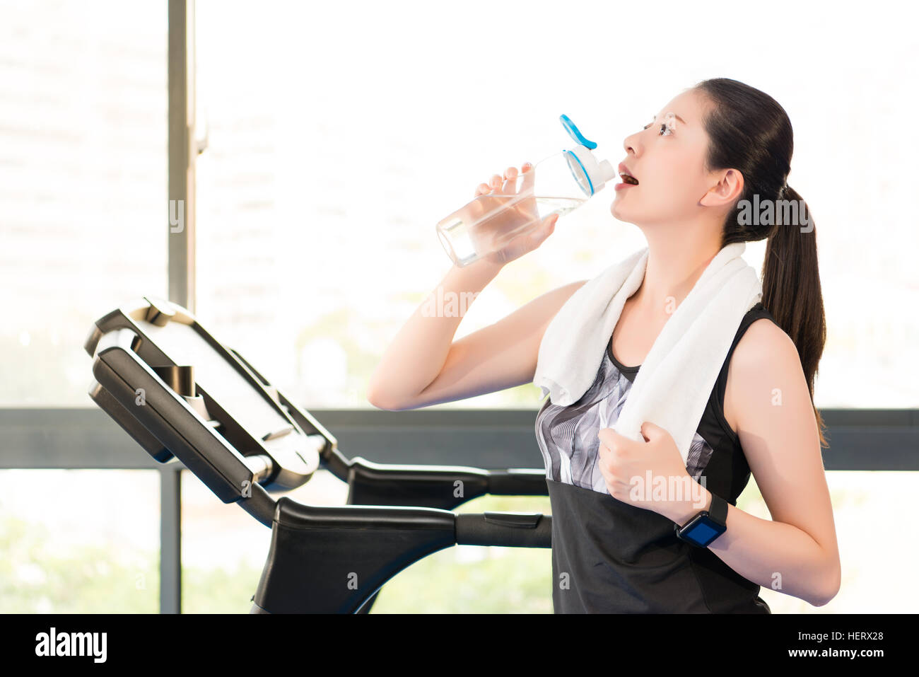 Beautiful asian woman take rest drinking water bottle after run ...