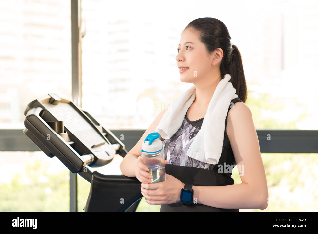 Beautiful asian woman take rest holding water bottle after run ...