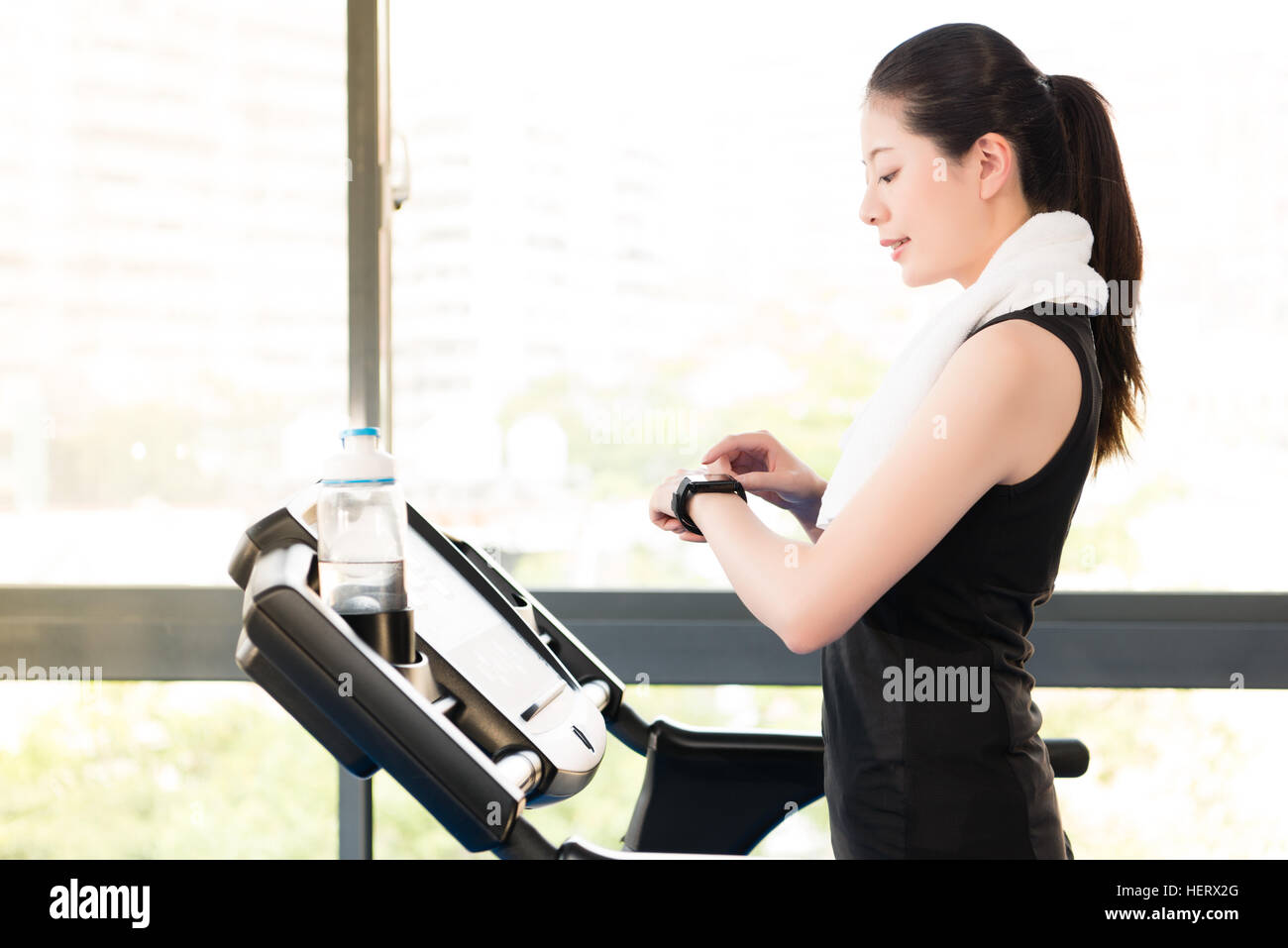 Beautiful asian woman running treadmill use smartwatch check pulse rate ...