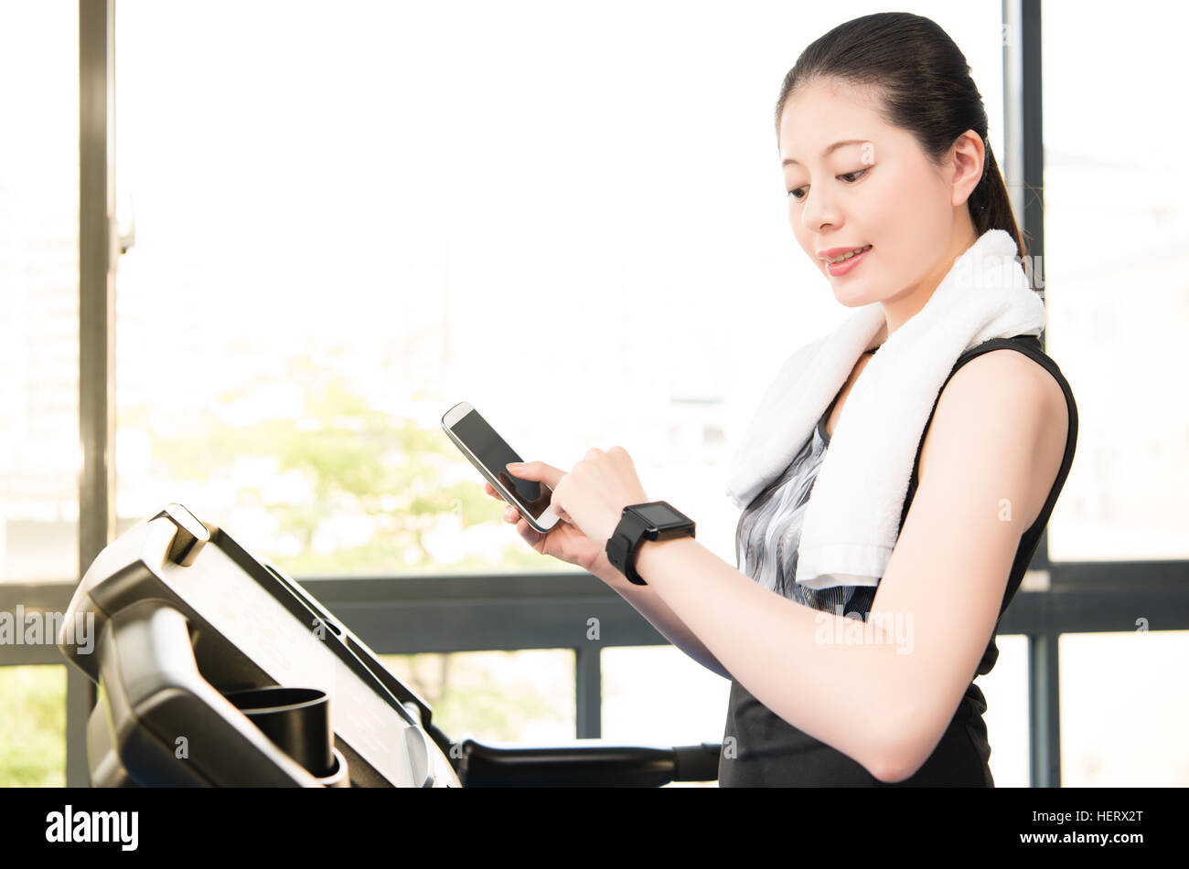 Beautiful asian woman running treadmill use smartwatch connect ...