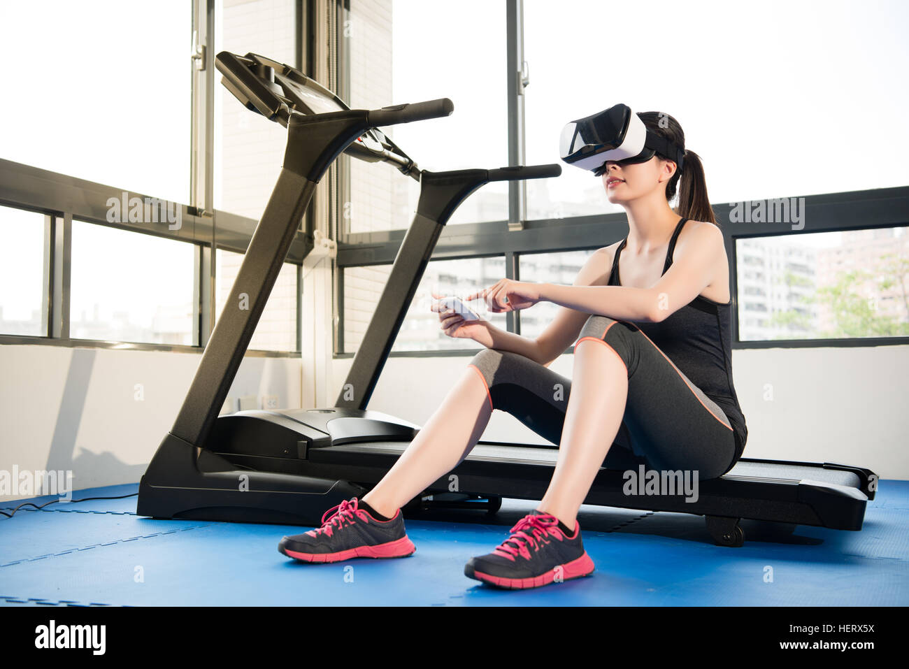 beauty asian woman rest on treadmill with virtual reality control by smartphone. VR headset ...
