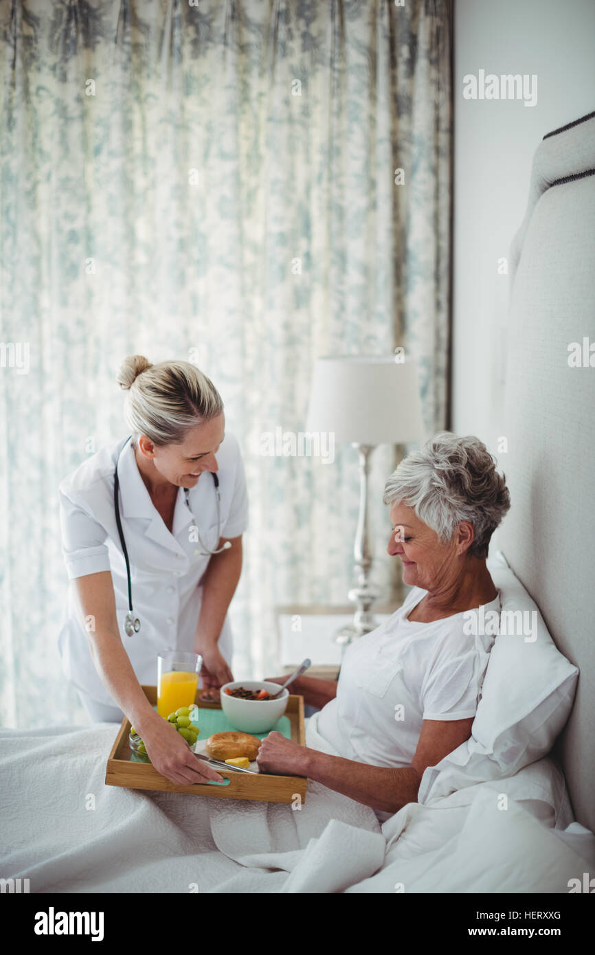 Doctor serving breakfast to senior patient in bedroom Stock Photo - Alamy