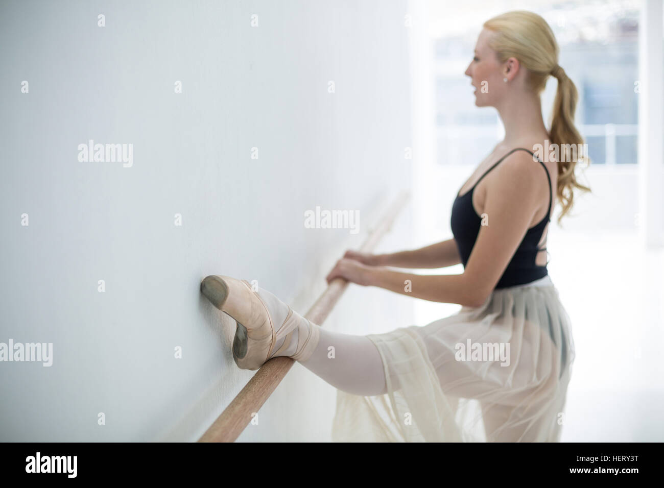 Ballerina stretching on a barre while practicing ballet dance in the ...
