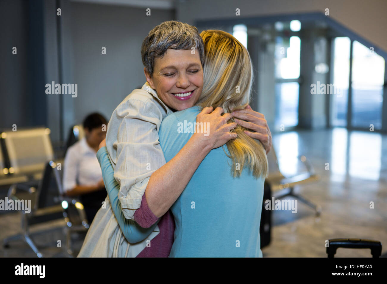 Friends embracing each other in the waiting area at airport terminal ...