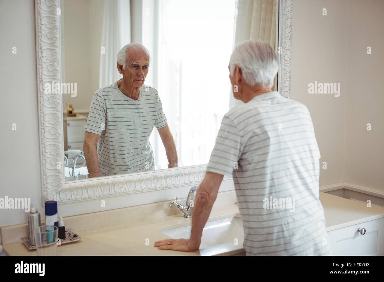 Senior man looking at mirror in bathroom Stock Photo - Alamy