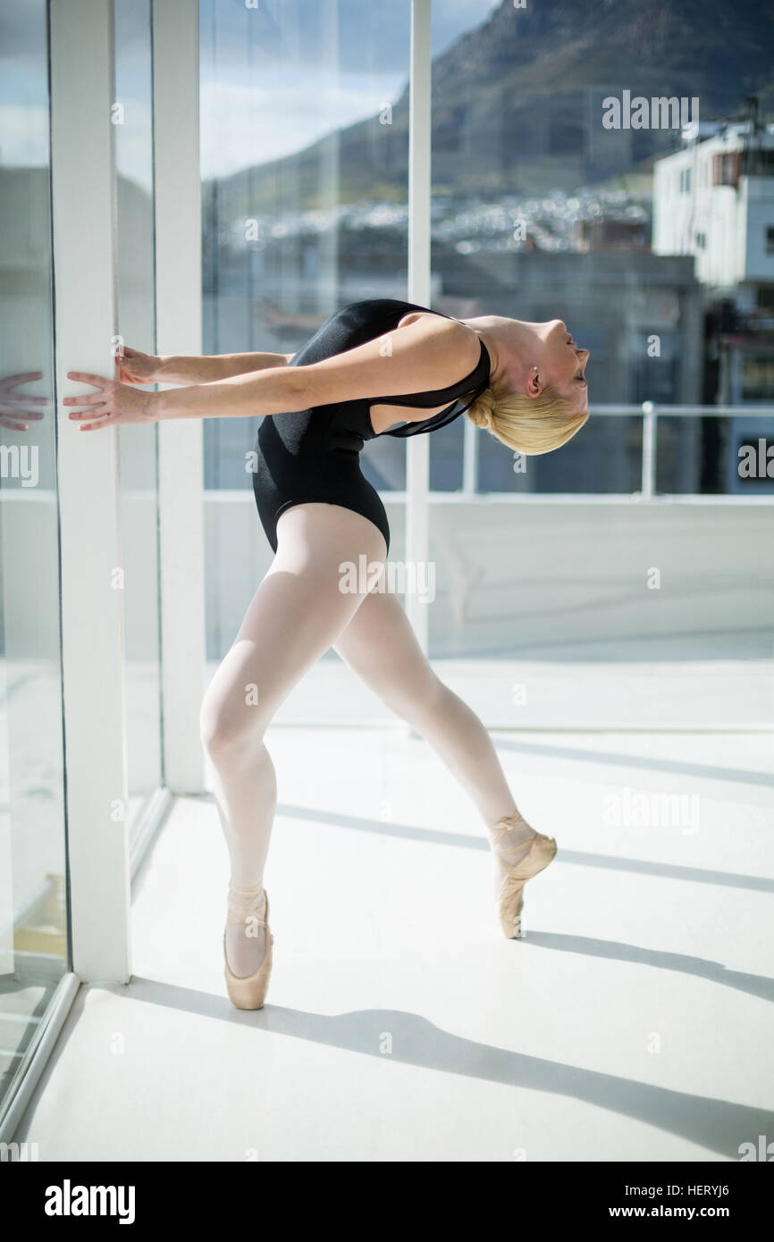Ballerina stretching on glass window while practicing ballet dance in ...