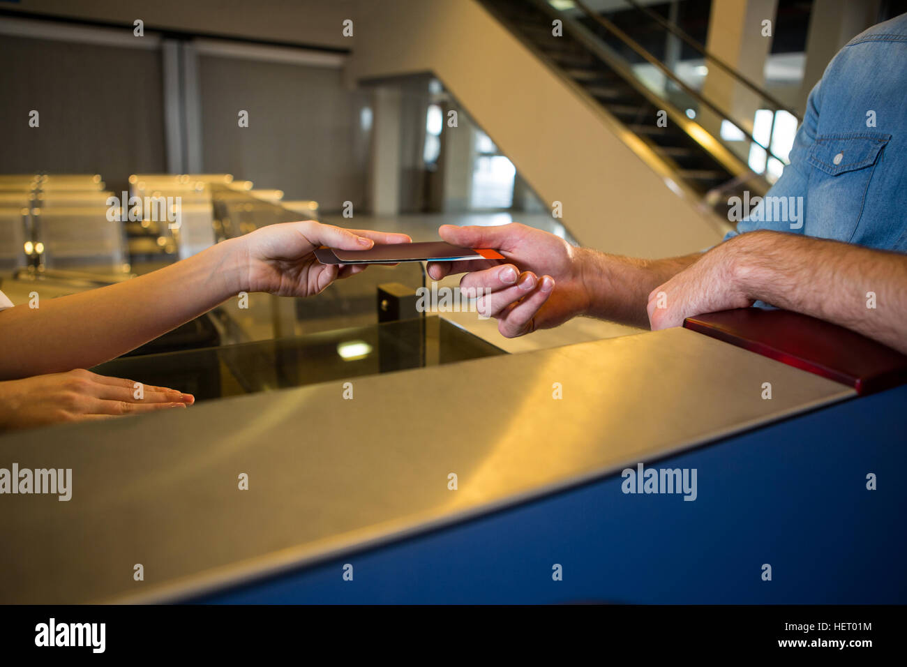 Close-up of female staff giving boarding pass at the check in desk ...