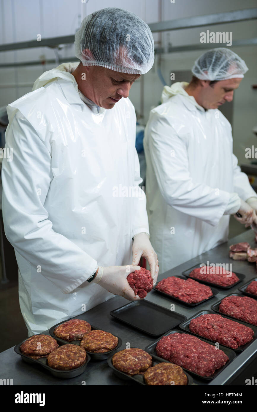 Butcher arranging minced meat in packaging tray in meat factory Stock ...