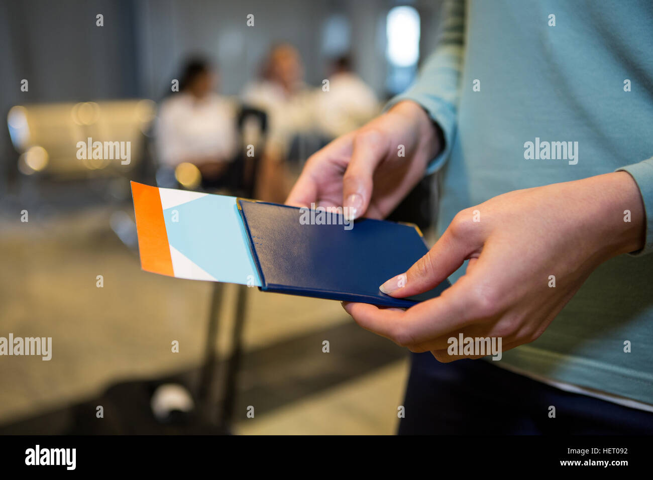 Mid-section of female passenger holding passport and boarding pass at ...