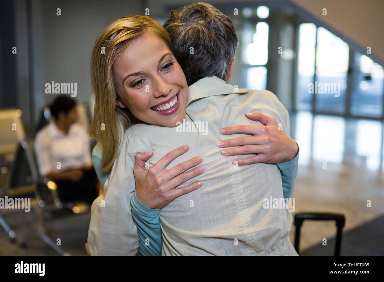 Friends embracing each other in the waiting area at airport terminal ...