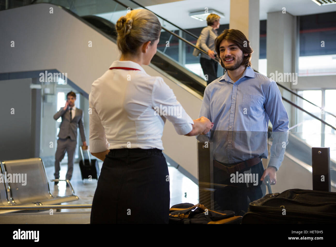 Female staff checking boarding pass of passengers at check-in counter ...