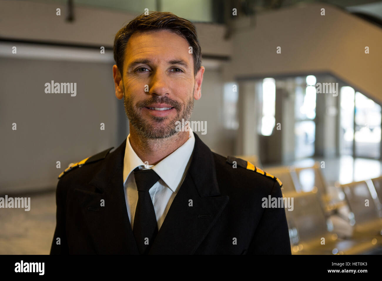 Portrait of smiling pilot standing in airport terminal Stock Photo - Alamy