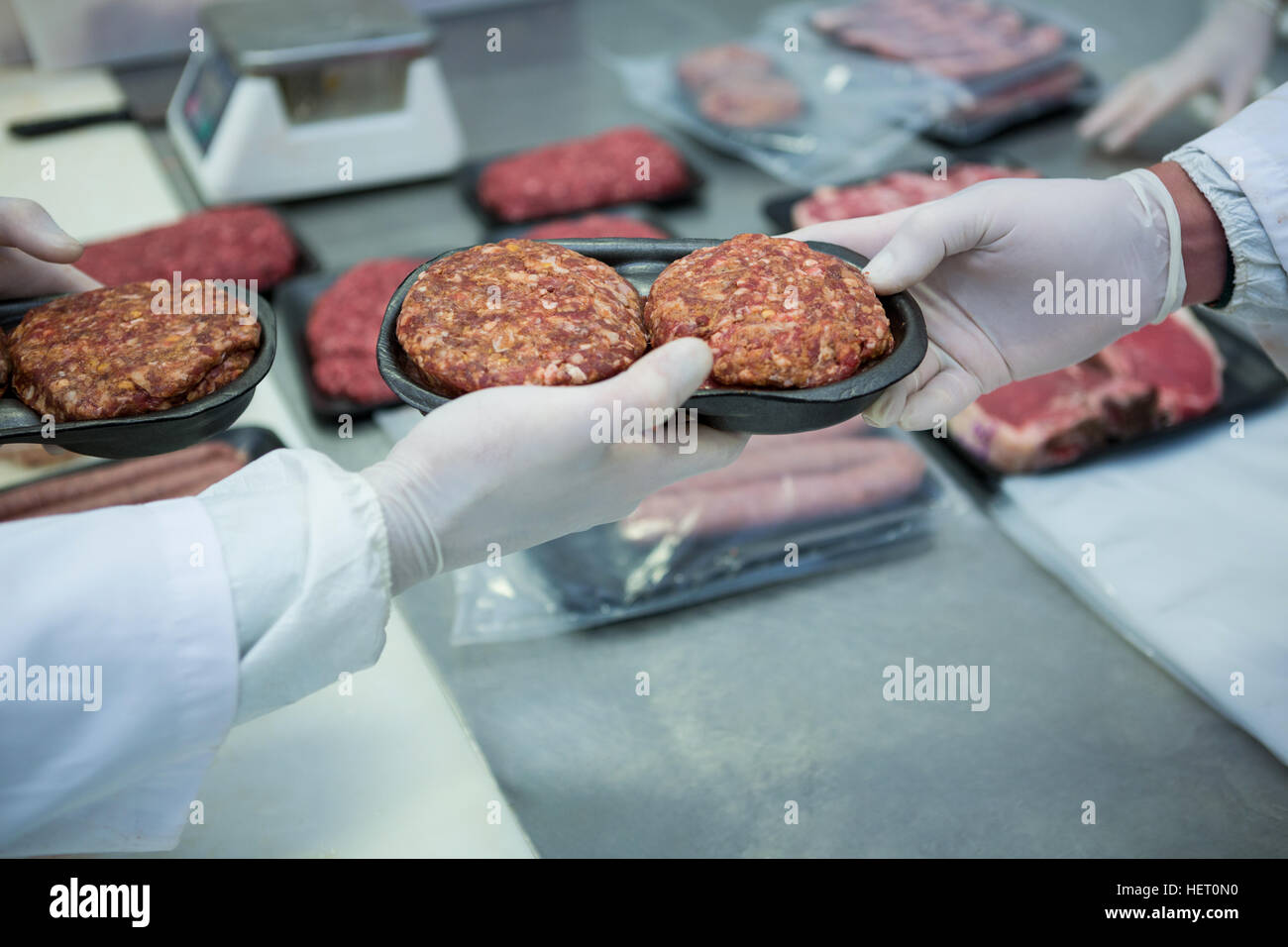 Butchers packing minced meat in a plastic packaging tray at meat ...
