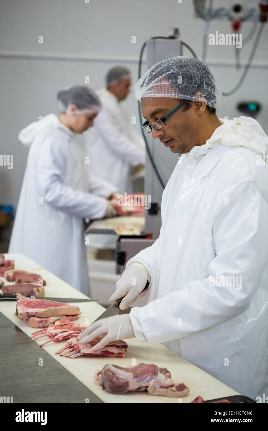 Butcher cutting meat at meat factory Stock Photo - Alamy