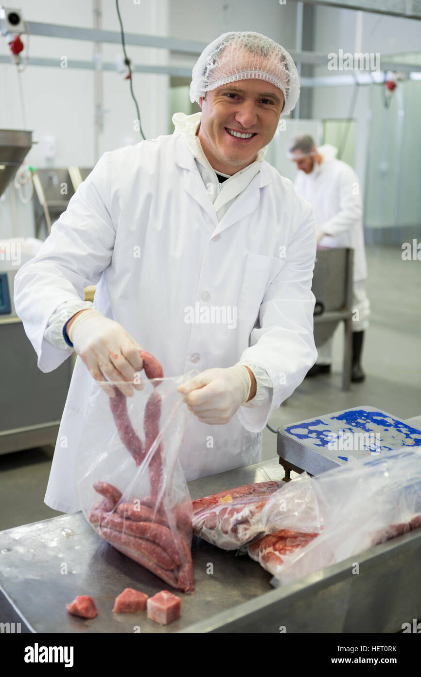 Portrait of male butcher packing raw sausages at meat factory Stock ...