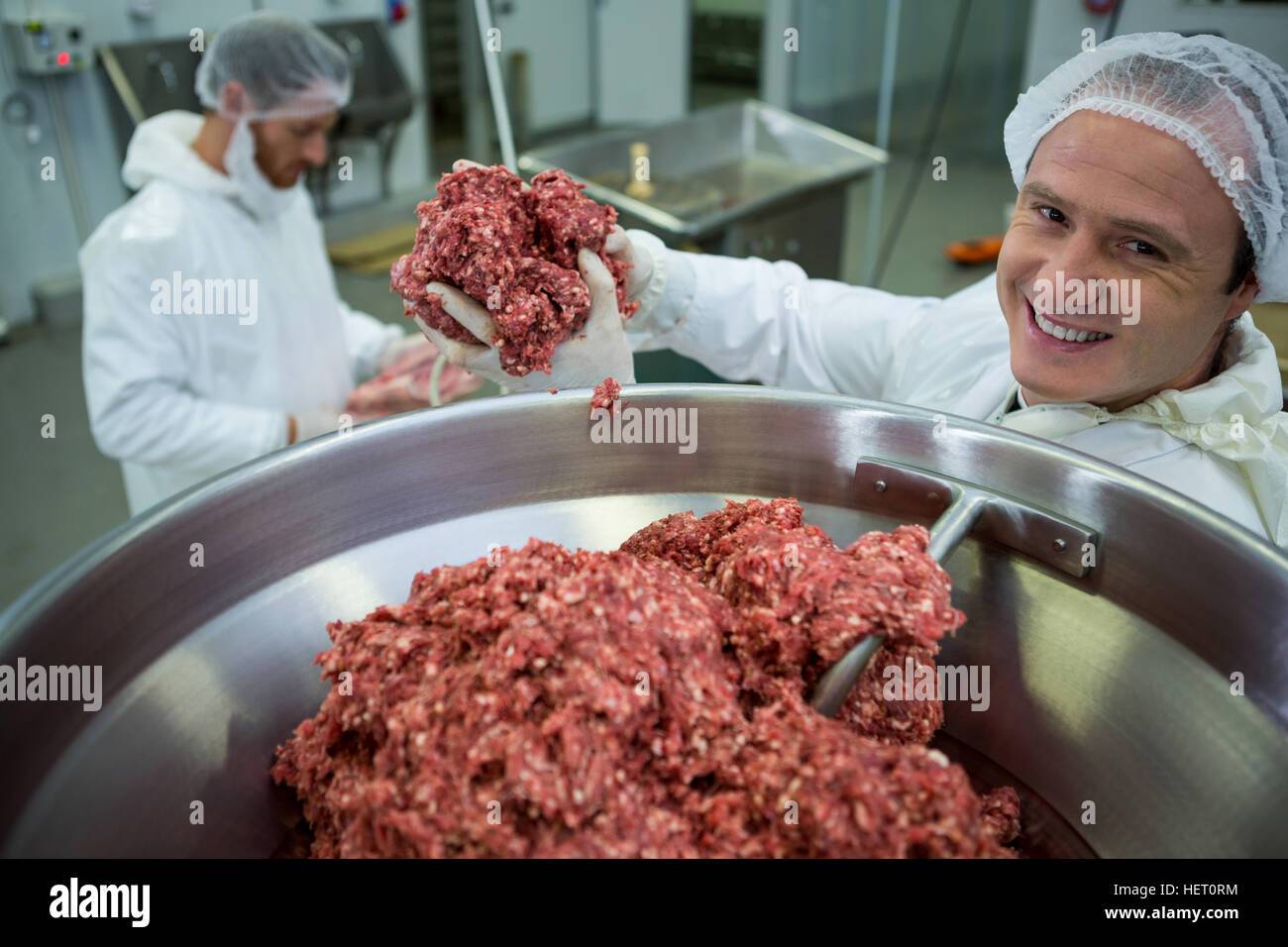 Butcher putting meat in mincer machine at meat factory Stock Photo - Alamy