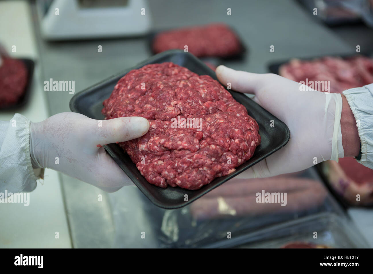 Butchers packing minced meat in a plastic packaging tray at meat ...
