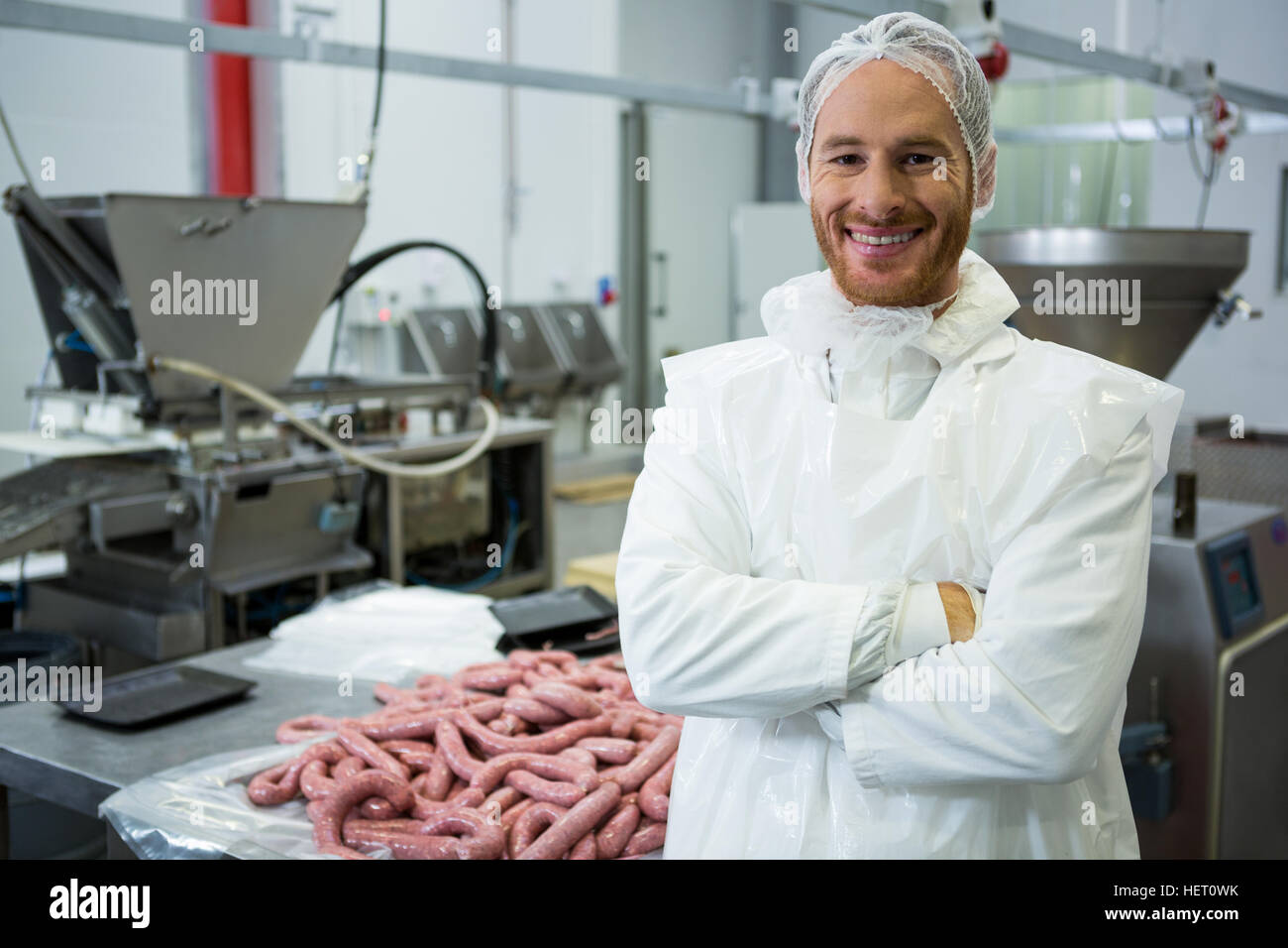 Portrait of male butcher standing with arms crossed at meat factory ...