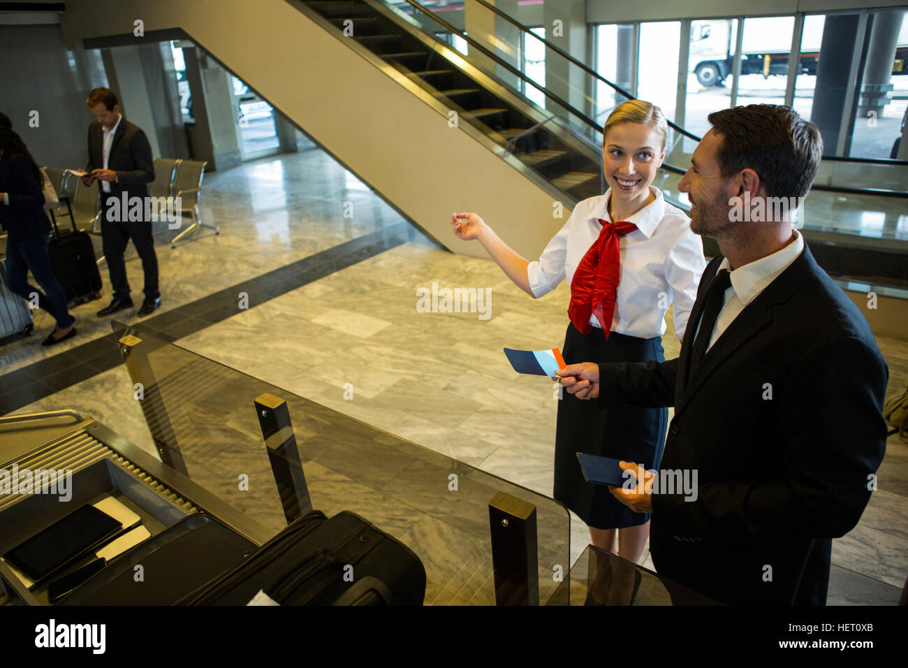 Female staff showing directions to businessman at airport terminal ...