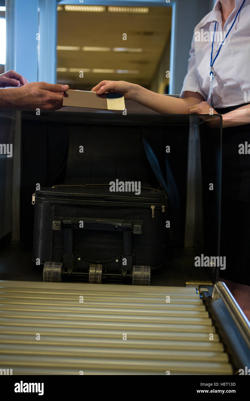 Mid section of female staff giving boarding pass at the check in desk ...
