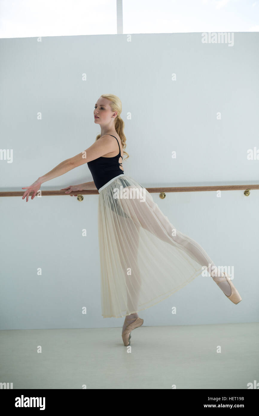Ballerina stretching on a barre while practicing ballet dance in the ...