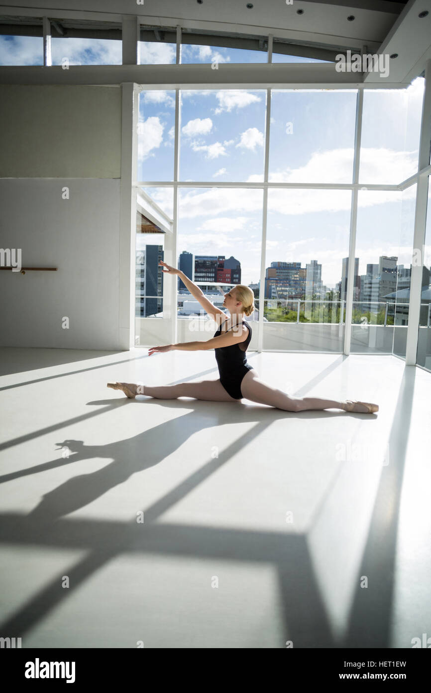 Ballerina stretching on the floor while practicing ballet dance at ...