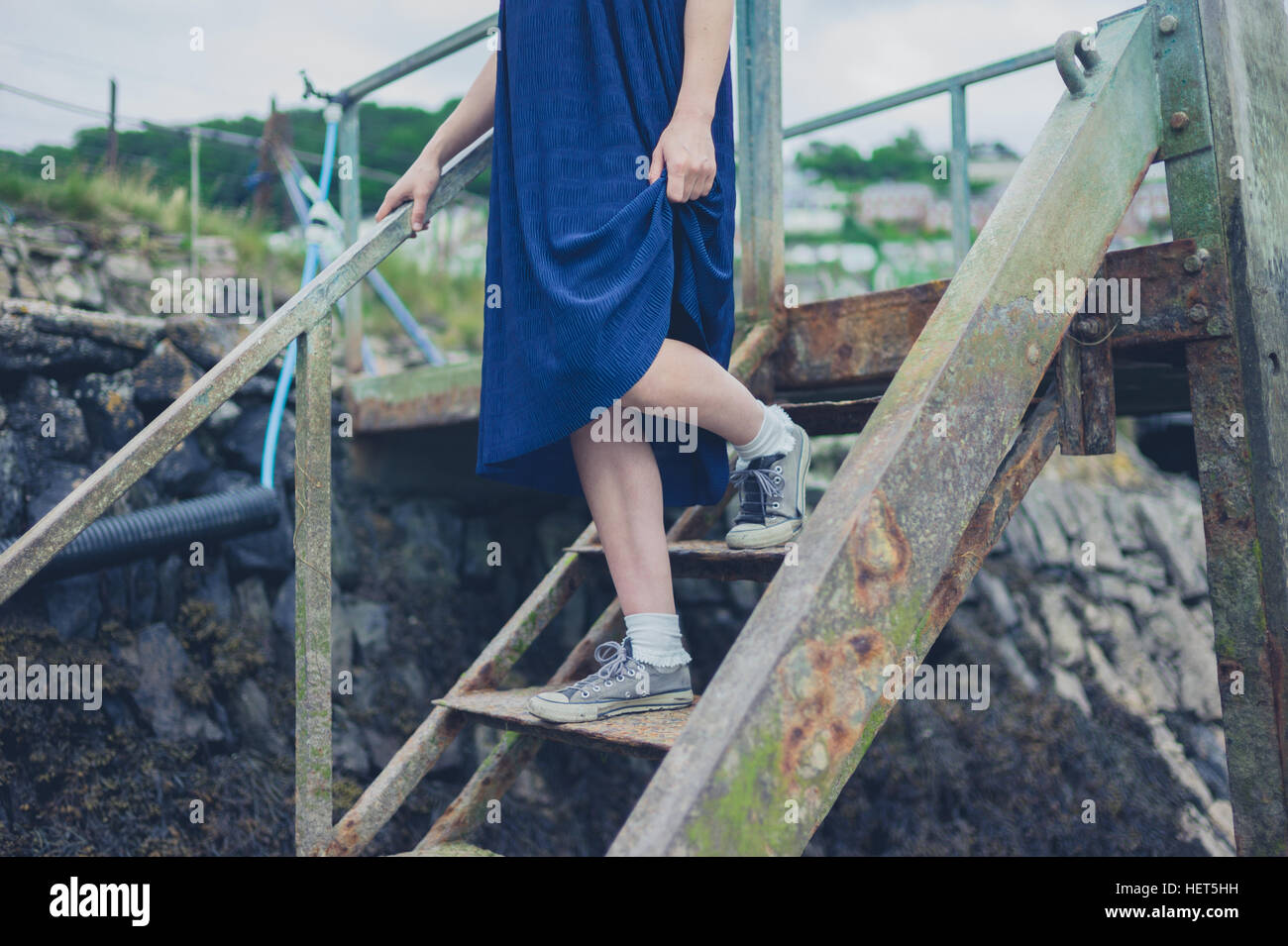 A young woman is walking down some rusty stairs outside Stock Photo - Alamy