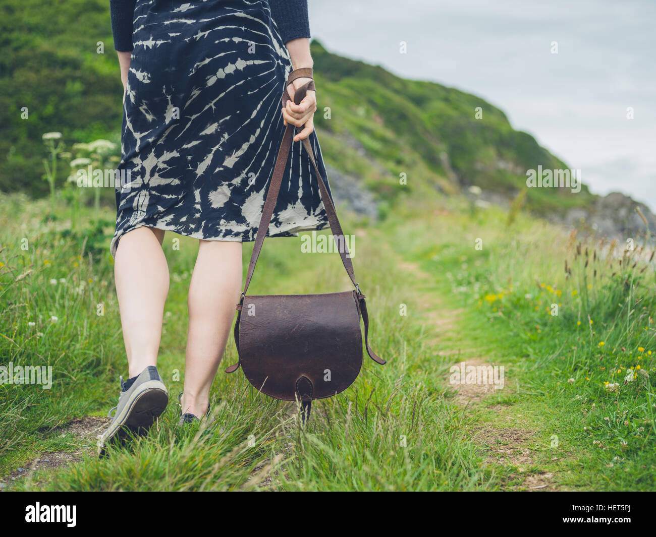 A young woman with a handbag is walking in nature Stock Photo - Alamy