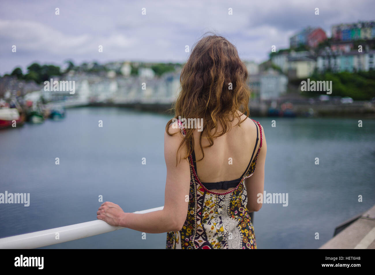 A young woman is standing by the railing in a small harbor Stock Photo ...