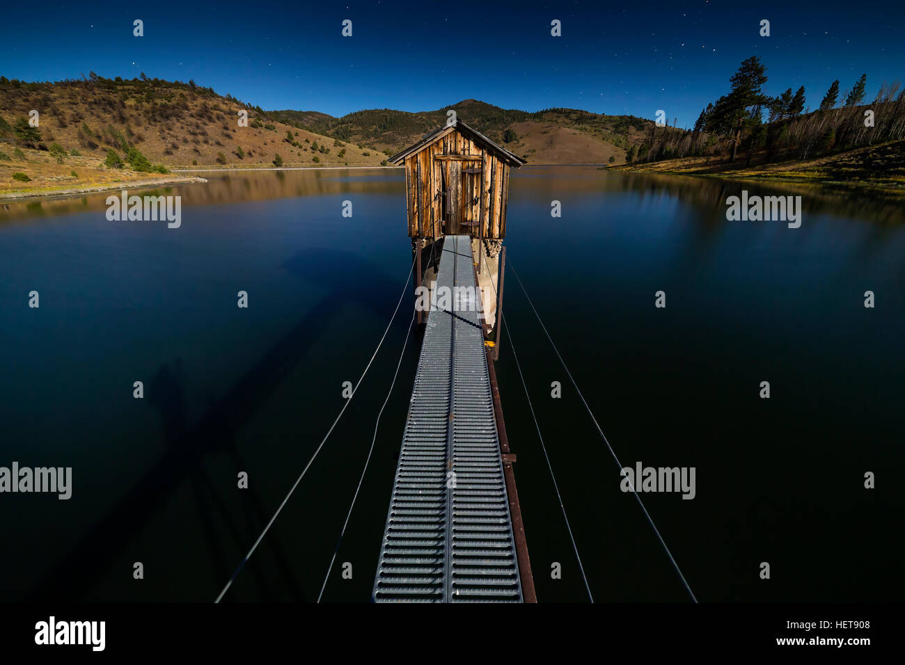Heenan Reservoir with damn gate building at night with stars. Lit by ...