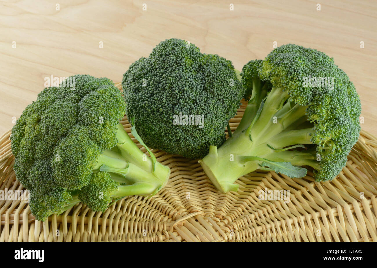 Heads of raw uncooked broccoli on wicker wooden plate as cooking ...
