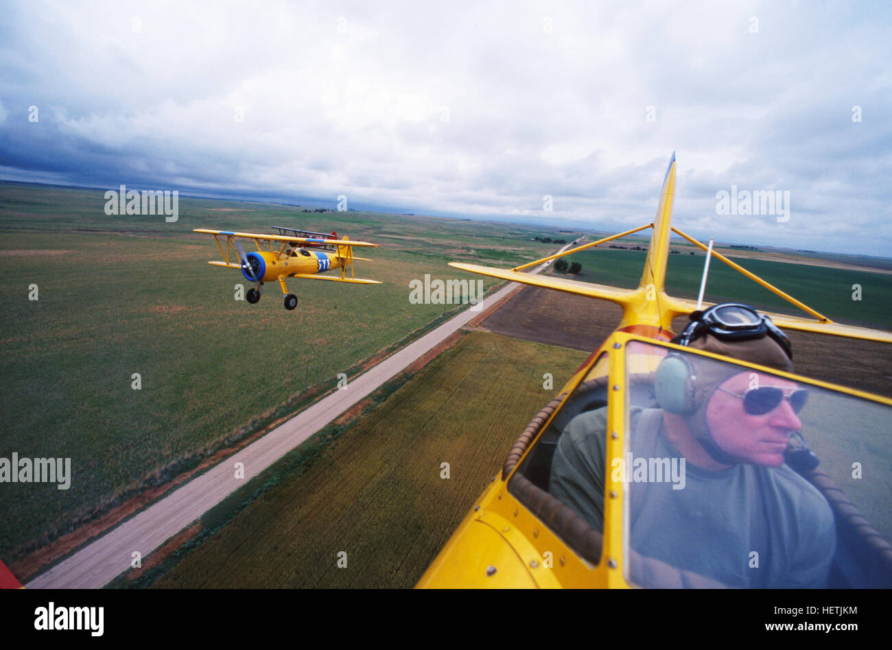 Two yellow Stearman biplanes in flight over the midwestern United ...