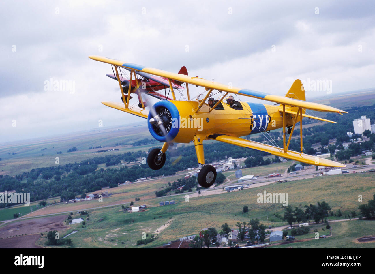 Two Stearman biplanes - one red, one yellow - make a synchronized turn ...