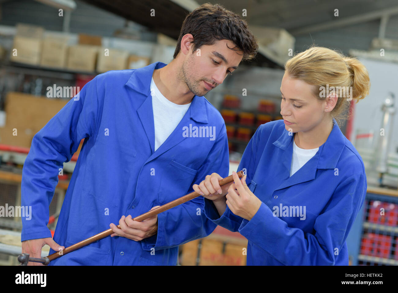 Two young manual workers inspecting copper pipe Stock Photo - Alamy